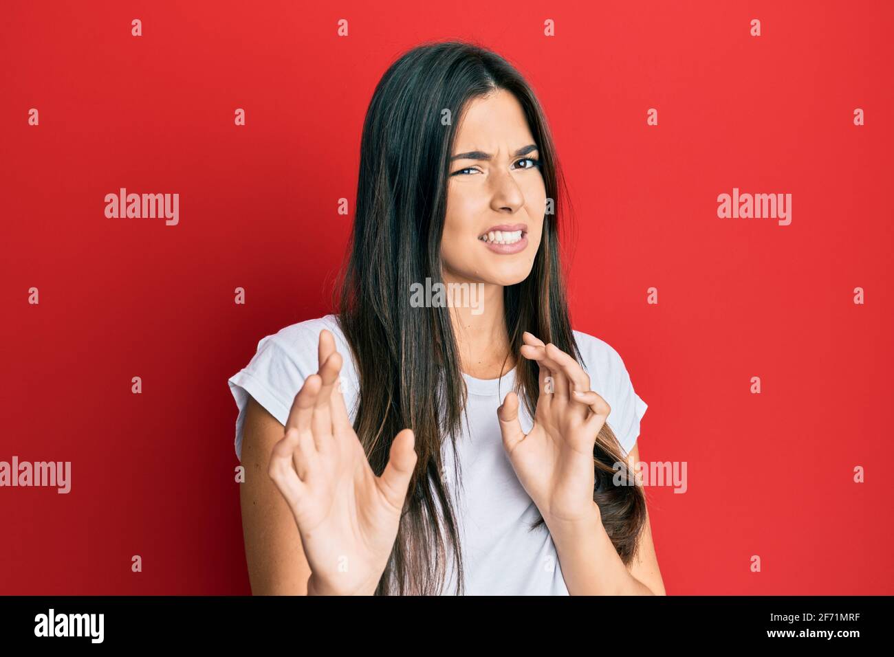 Young brunette woman wearing casual white tshirt over red background ...