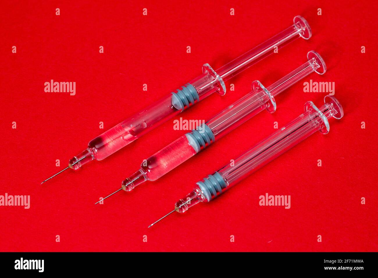 Syringes isolated on red background Stock Photo - Alamy