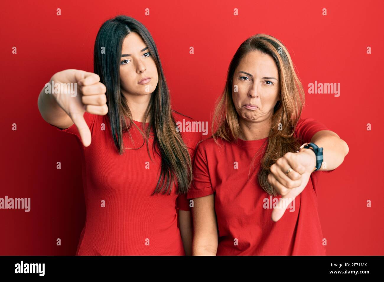 Hispanic family of mother and daughter wearing casual clothes over red ...