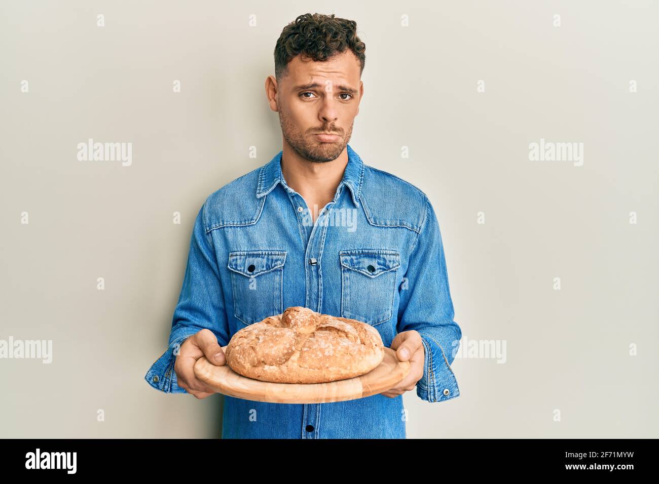 Young hispanic man holding bread depressed and worry for distress ...