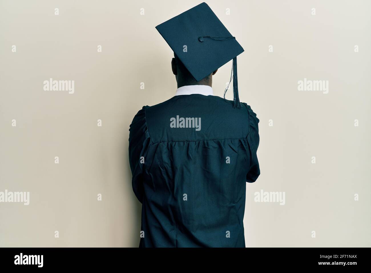 Handsome black man wearing graduation cap and ceremony robe standing ...