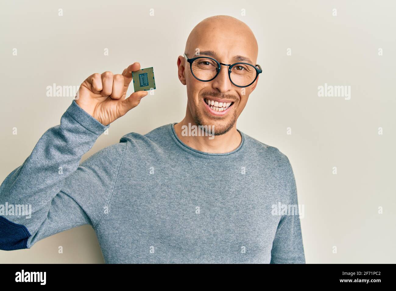 Bald man with beard holding cpu computer processor looking positive and ...