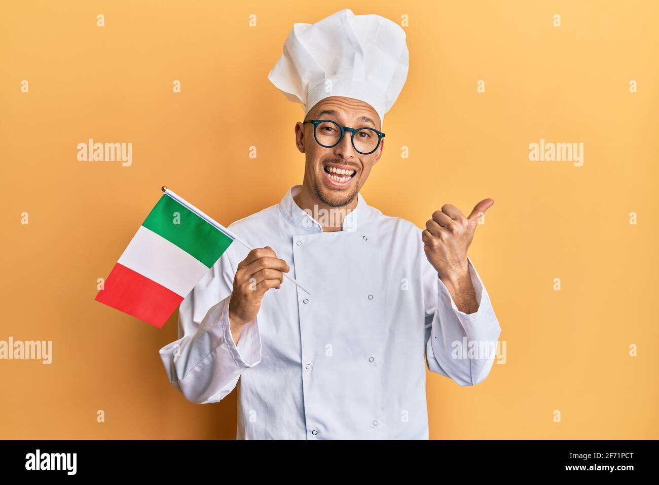 Bald man with beard wearing professional cook uniform holding italian ...