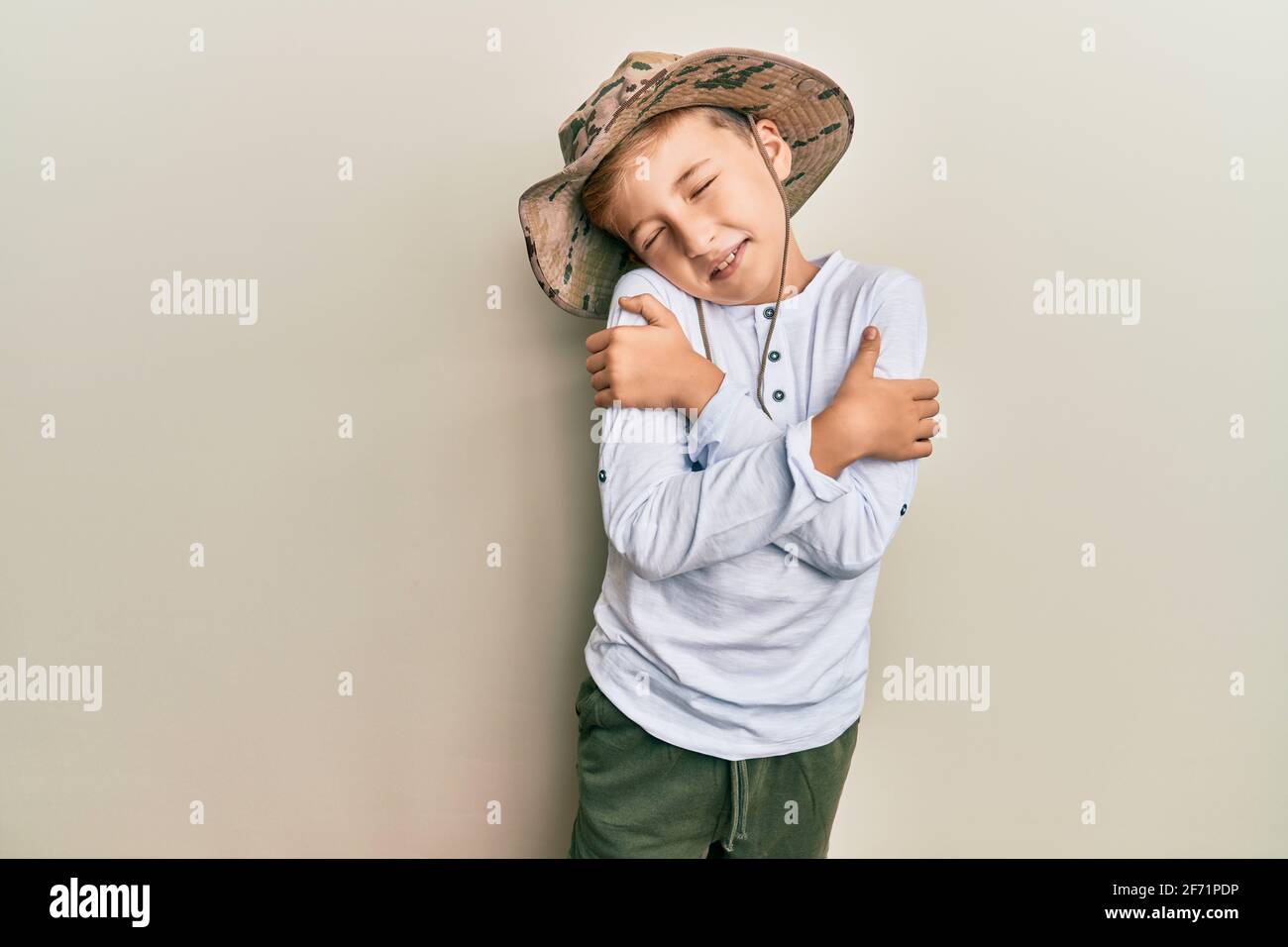Little caucasian boy kid wearing explorer hat hugging oneself happy and ...