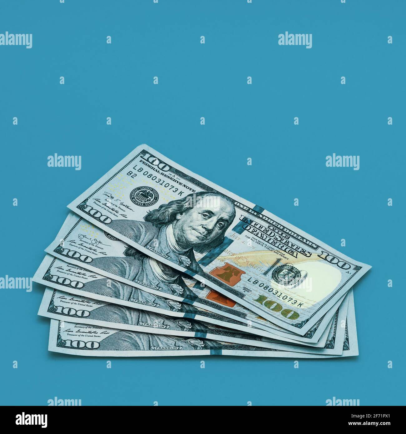A wad of hundred-dollar cash fanned out on a blue background. A place ...