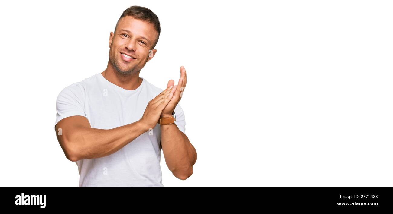 Handsome muscle man wearing casual white tshirt clapping and applauding ...