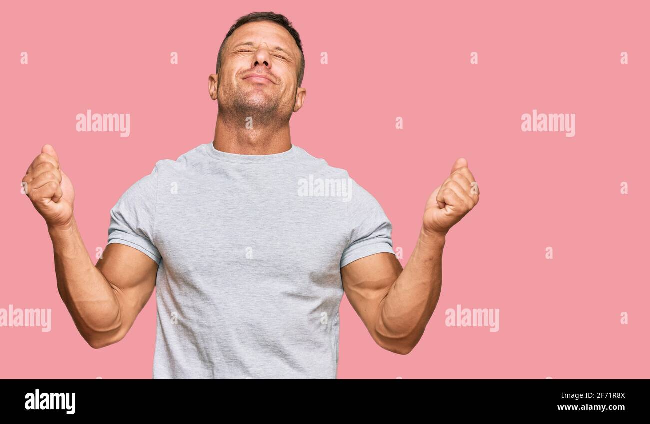 Handsome muscle man wearing casual grey tshirt very happy and excited ...