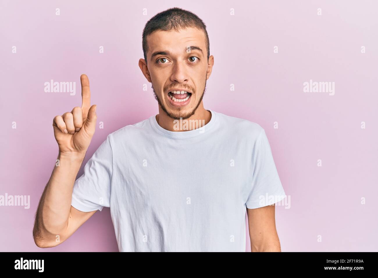 Hispanic young man wearing casual white t shirt smiling with an idea or ...