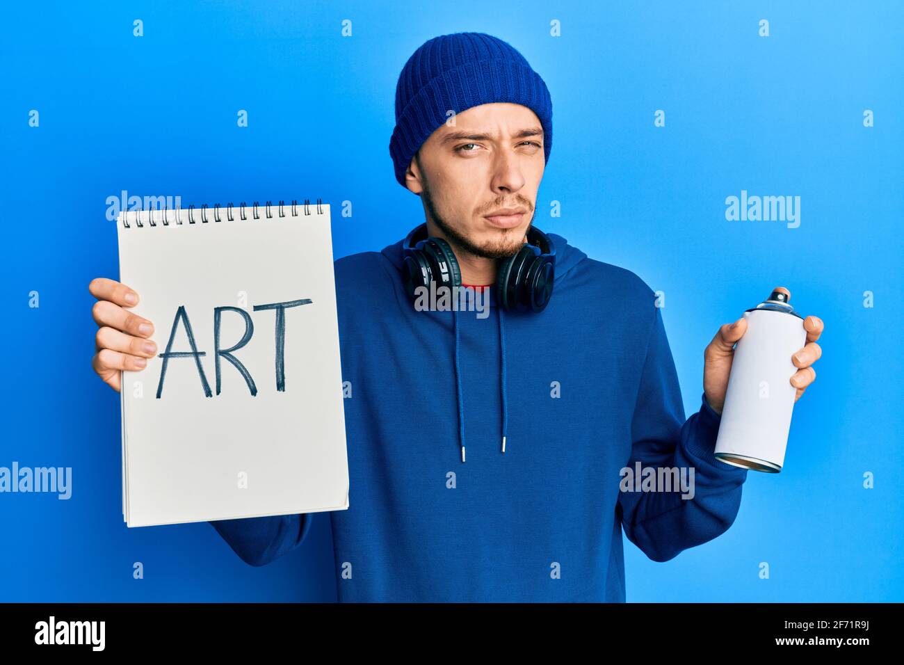 Hispanic young man wearing sweatshirt holding graffiti spray clueless ...