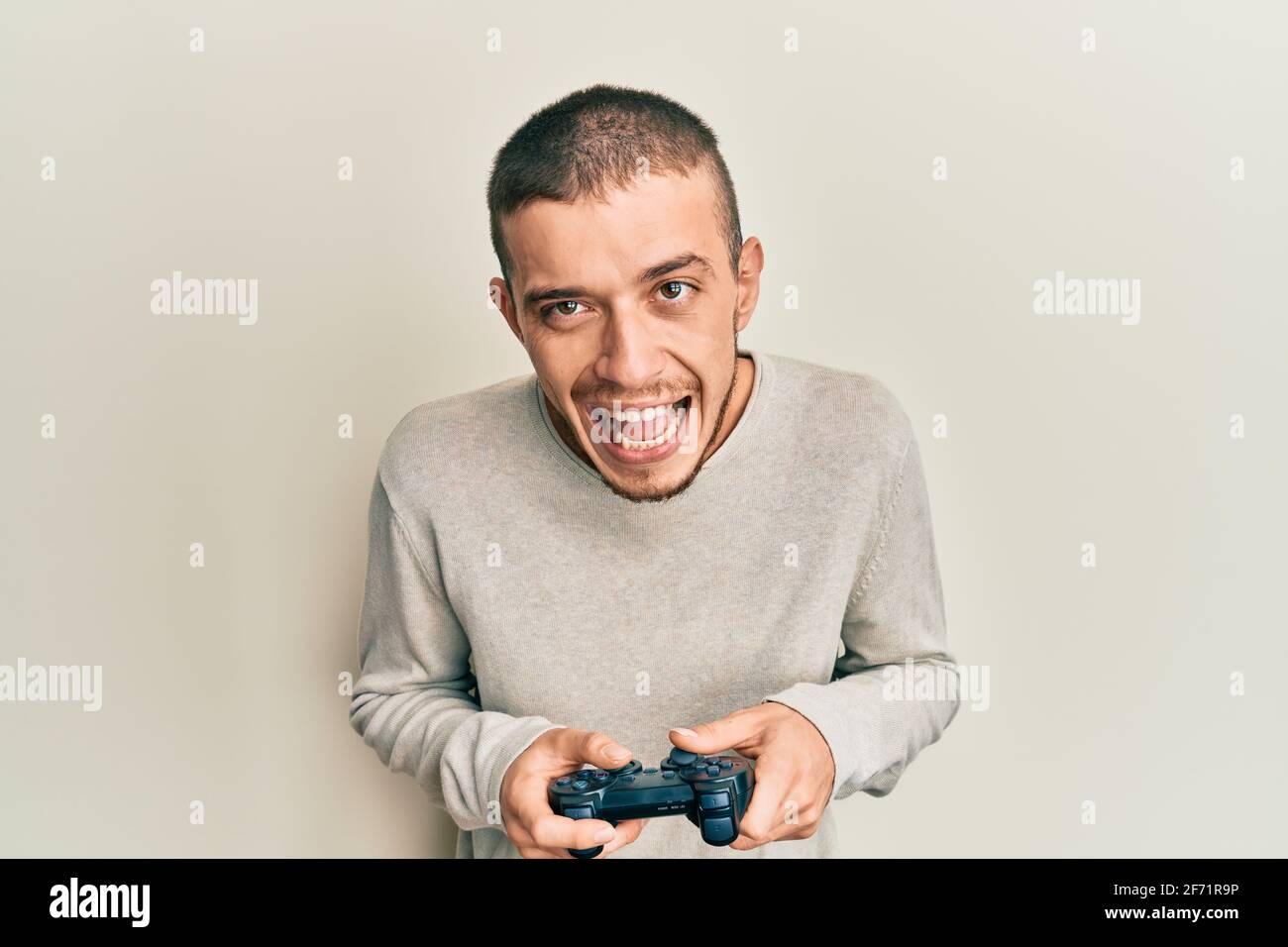 Hispanic young man playing video game holding controller smiling and ...