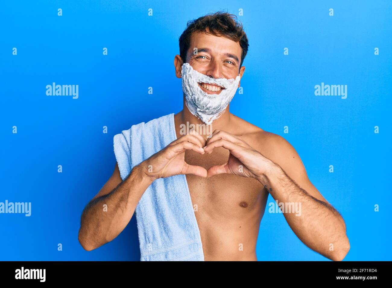 Handsome man saving beard with shave foam over face smiling in love ...
