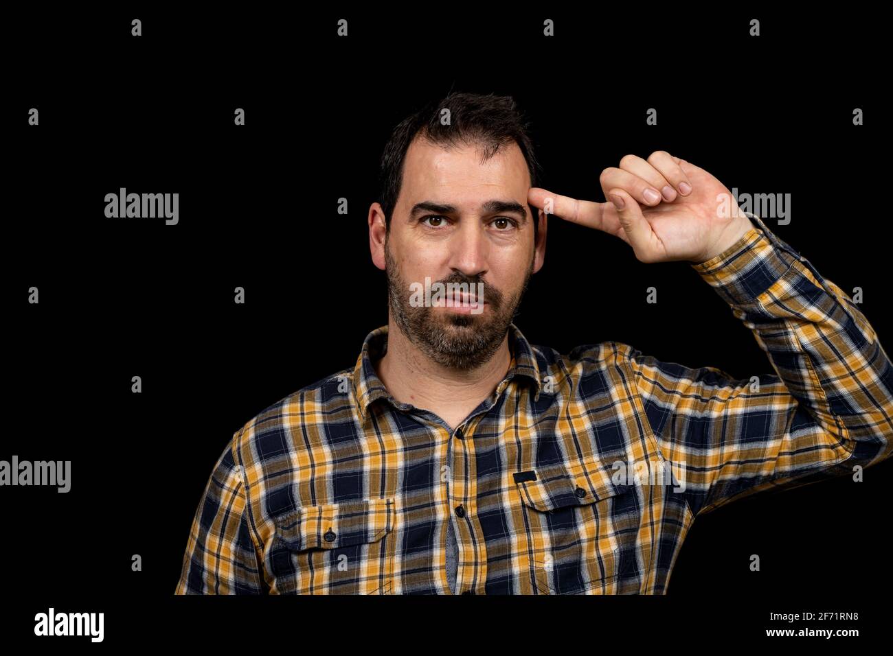 Portrait of bearded man in yellow checkered shirt pointing his head ...