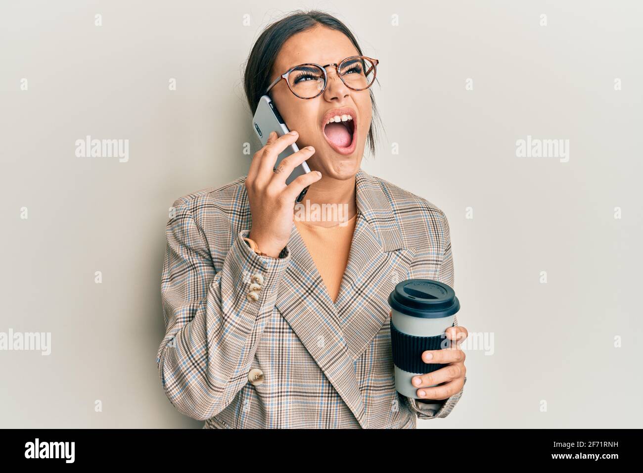 Young brunette woman using smartphone and drinking a cup of coffee ...