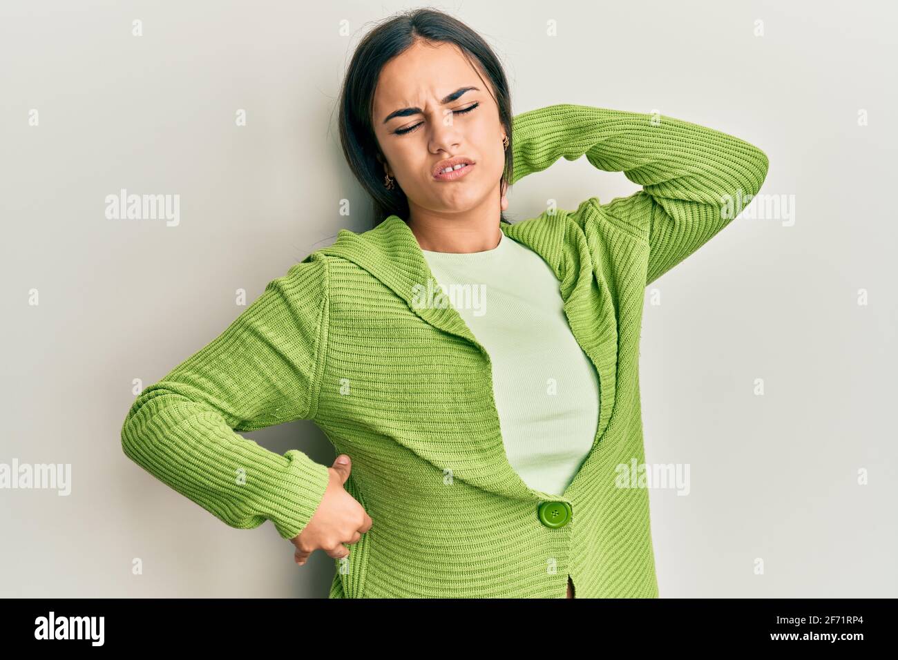 Young brunette woman wearing casual clothes stretching back, tired and ...