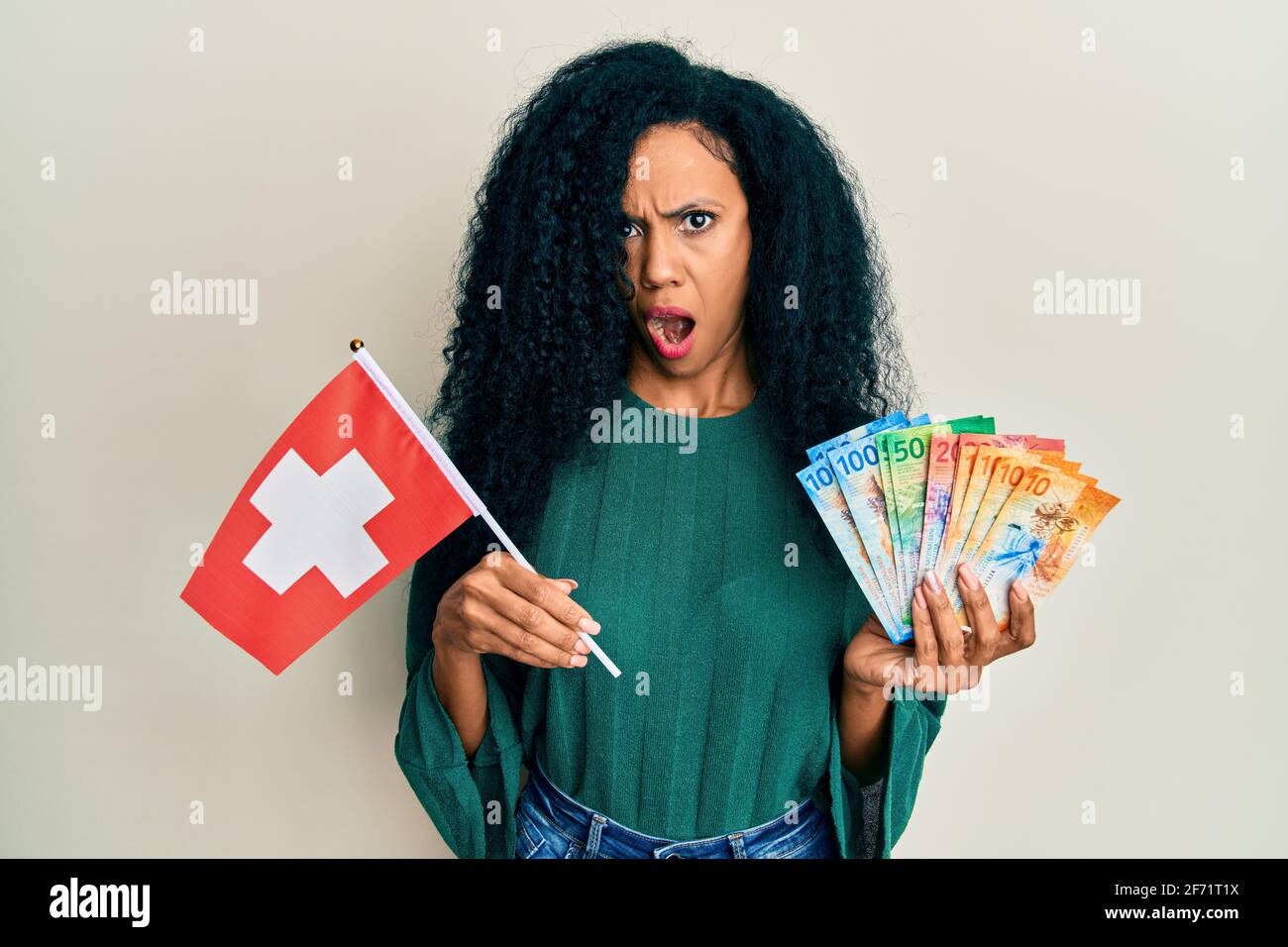 Middle age african american woman holding switzerland flag and franc ...
