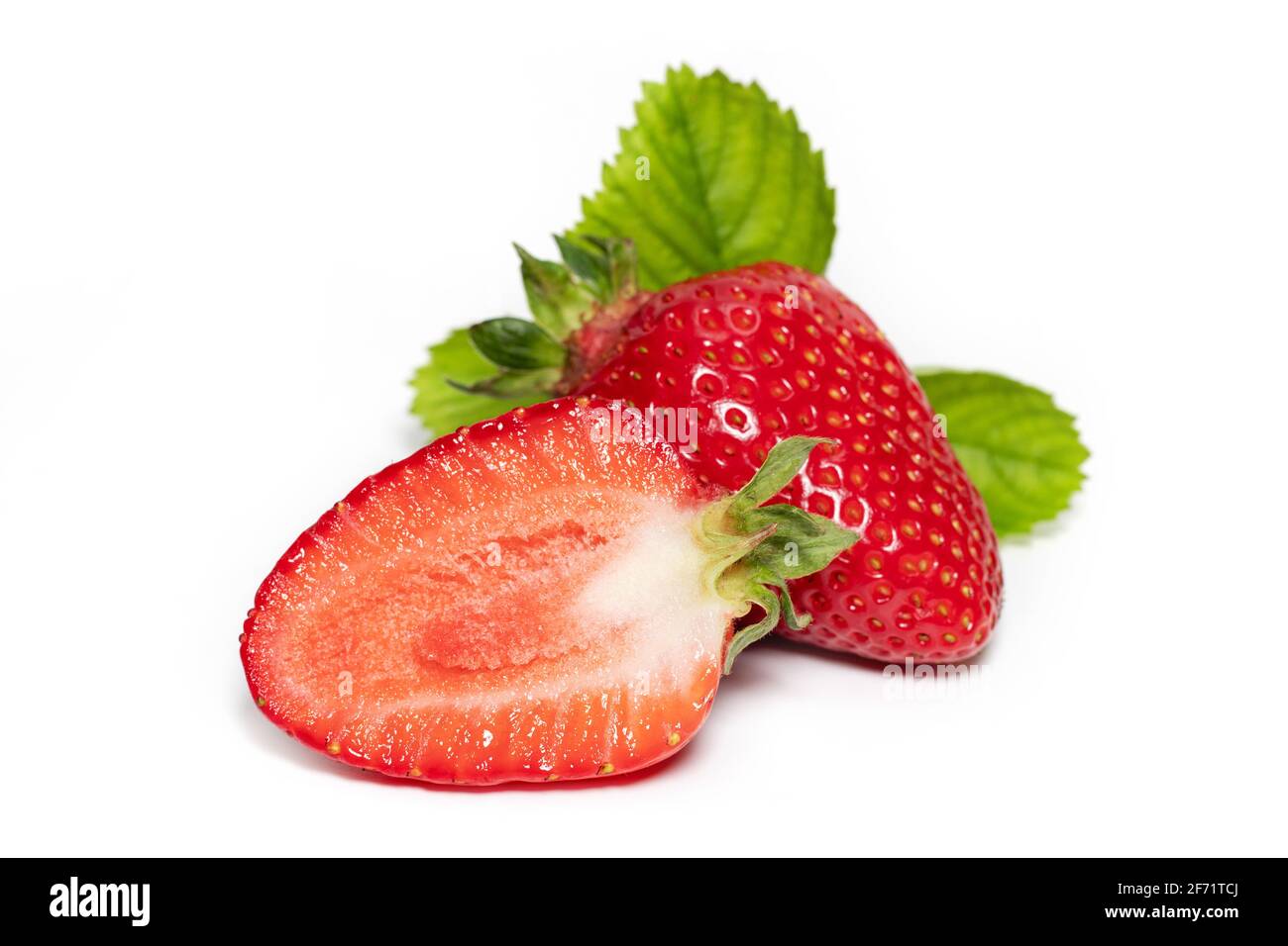 Isolated strawberries. Three fruits, one cut in half on white ...