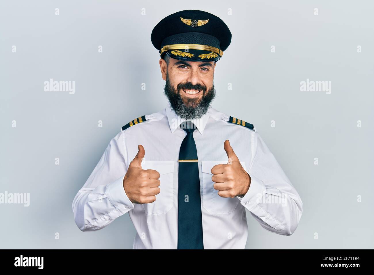 Young hispanic man wearing airplane pilot uniform success sign doing ...