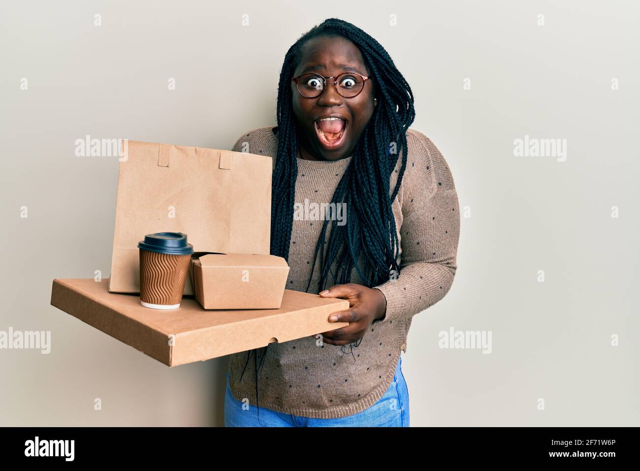 Young black woman with braids holding take away food celebrating crazy ...
