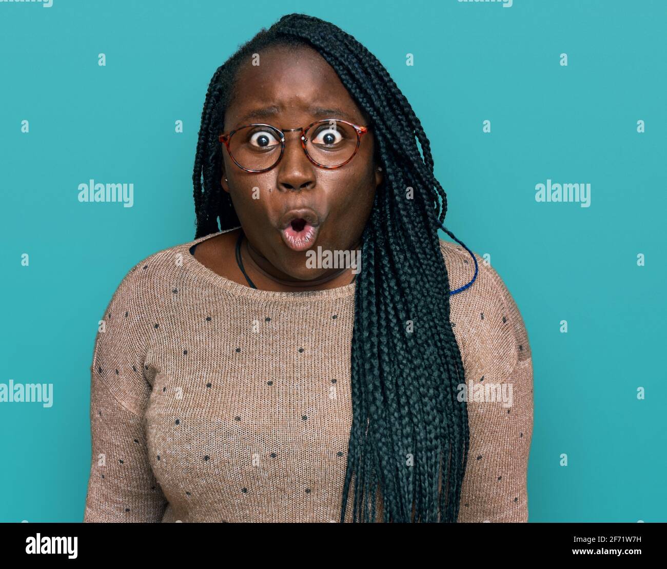 Young black woman with braids wearing casual clothes and glasses scared ...