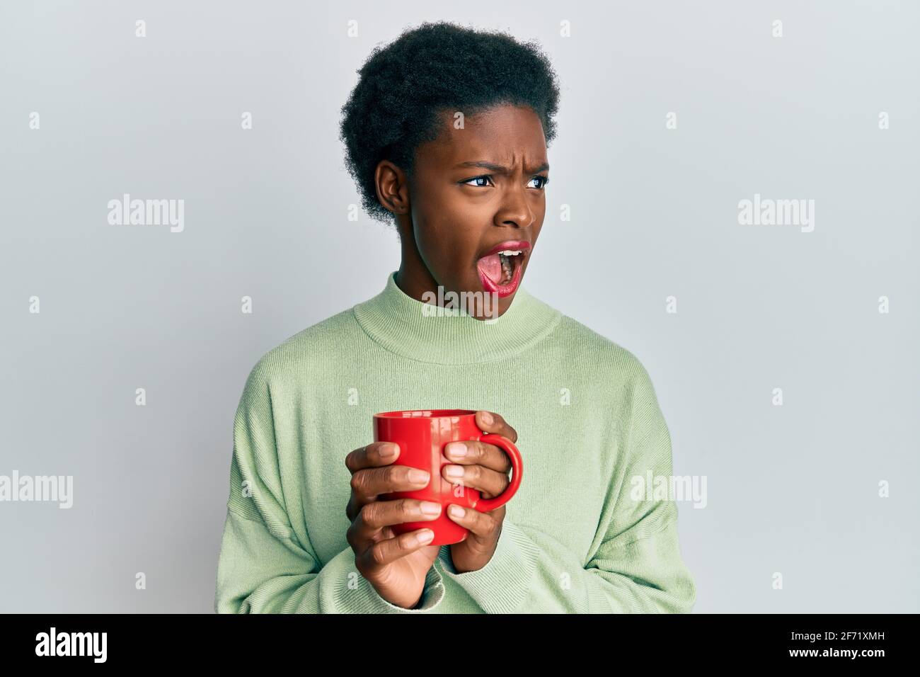 Young african american girl drinking a cup of coffee angry and mad ...