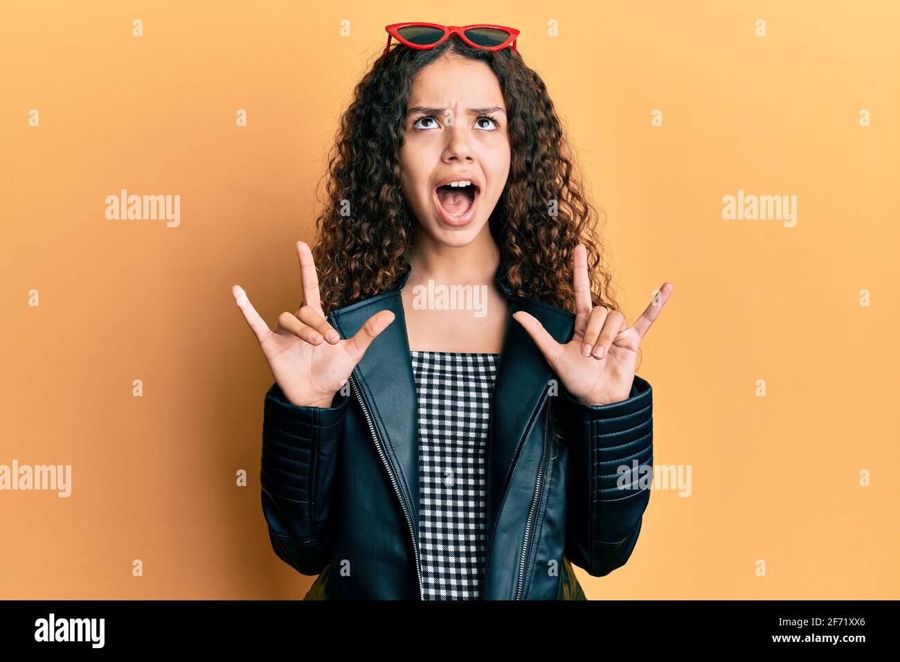 Teenager hispanic girl doing rock gesture angry and mad screaming ...