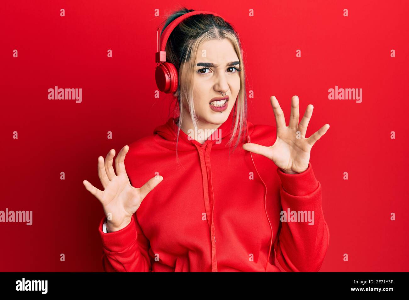 Young modern girl wearing gym clothes and using headphones disgusted ...