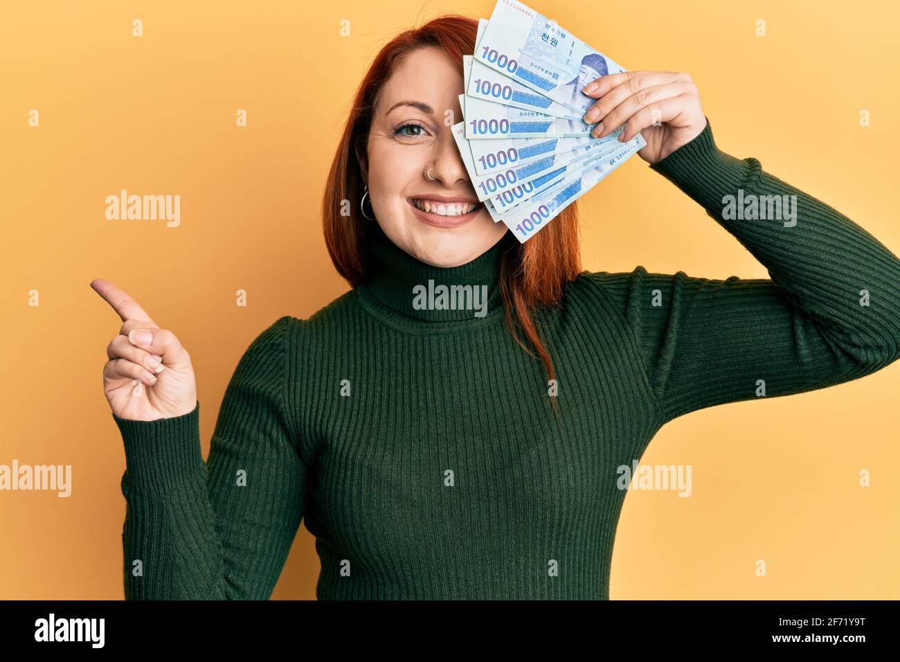 Beautiful redhead woman holding 1000 south korean won banknotes over ...