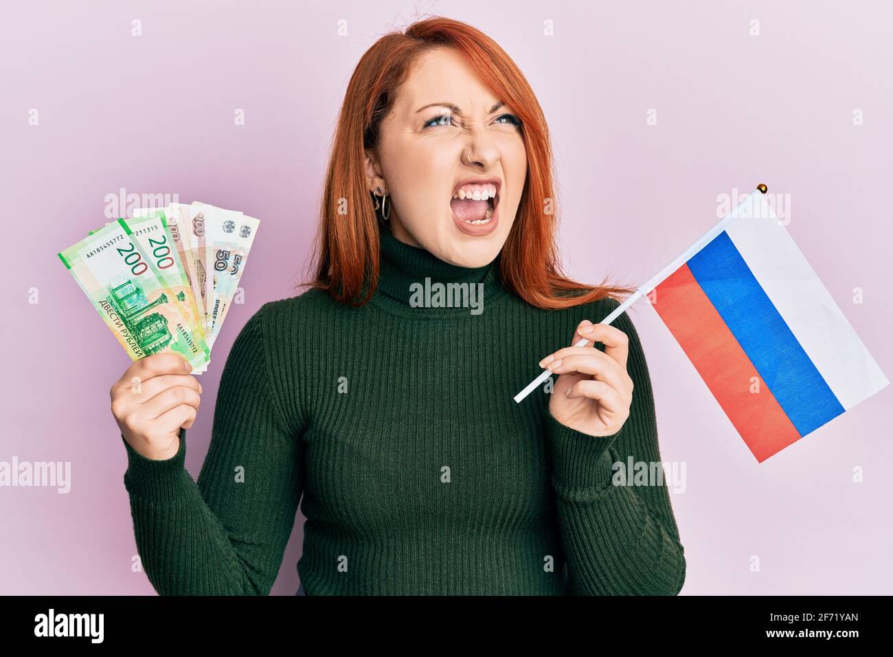 Beautiful redhead woman holding russian ruble banknotes and russia flag ...
