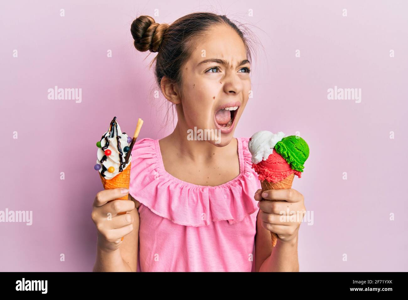 Beautiful brunette little girl eating ice cream cones angry and mad ...