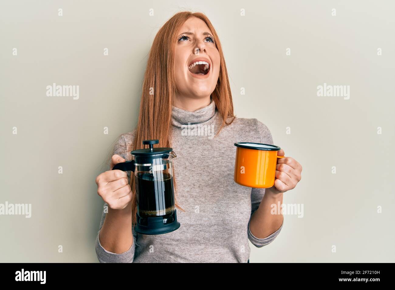 Young irish woman drinking italian coffee angry and mad screaming ...