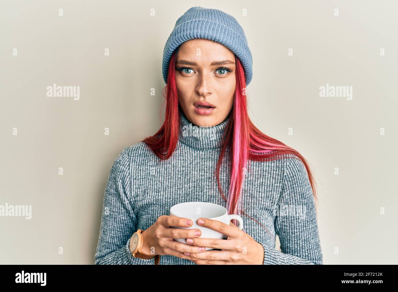 Young caucasian woman wearing winter cap and drinking a cup of hot ...