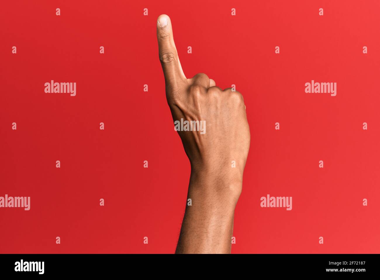 Hand of hispanic man over red isolated background counting number one ...