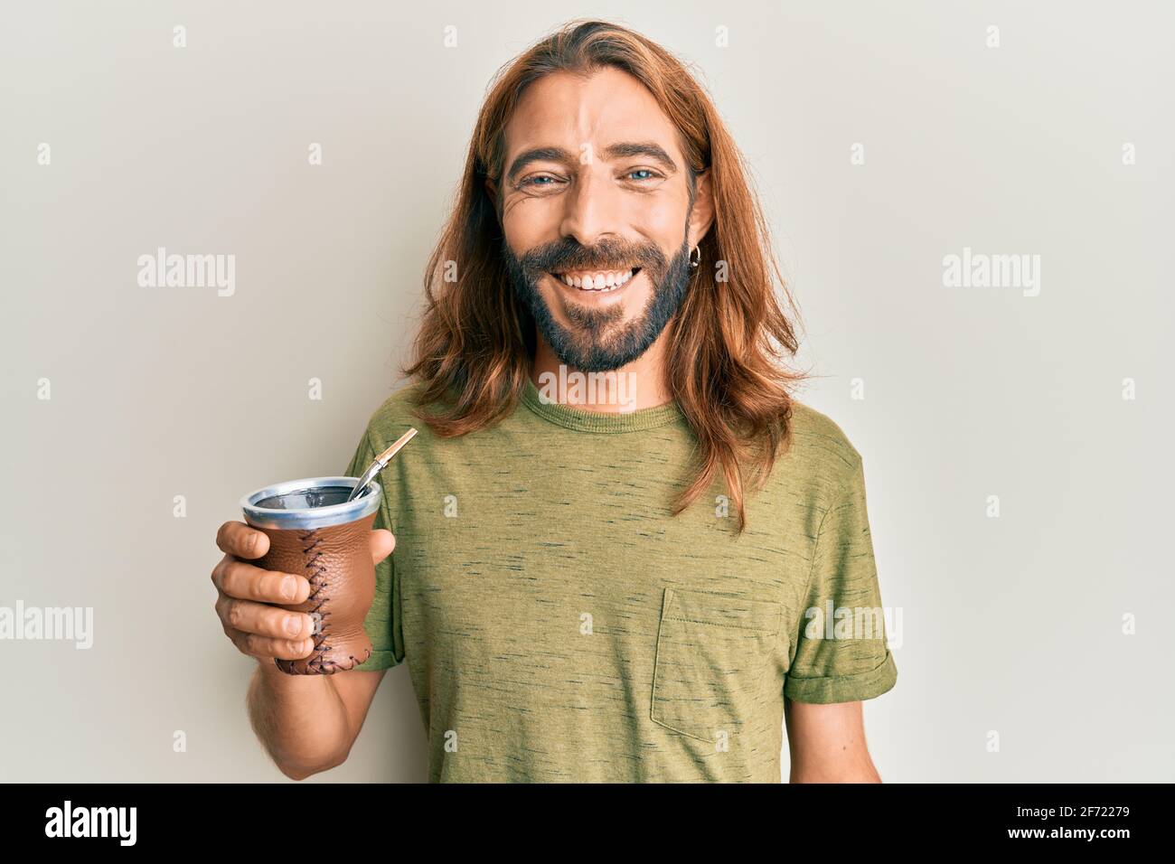 Attractive man with long hair and beard drinking mate infusion looking ...
