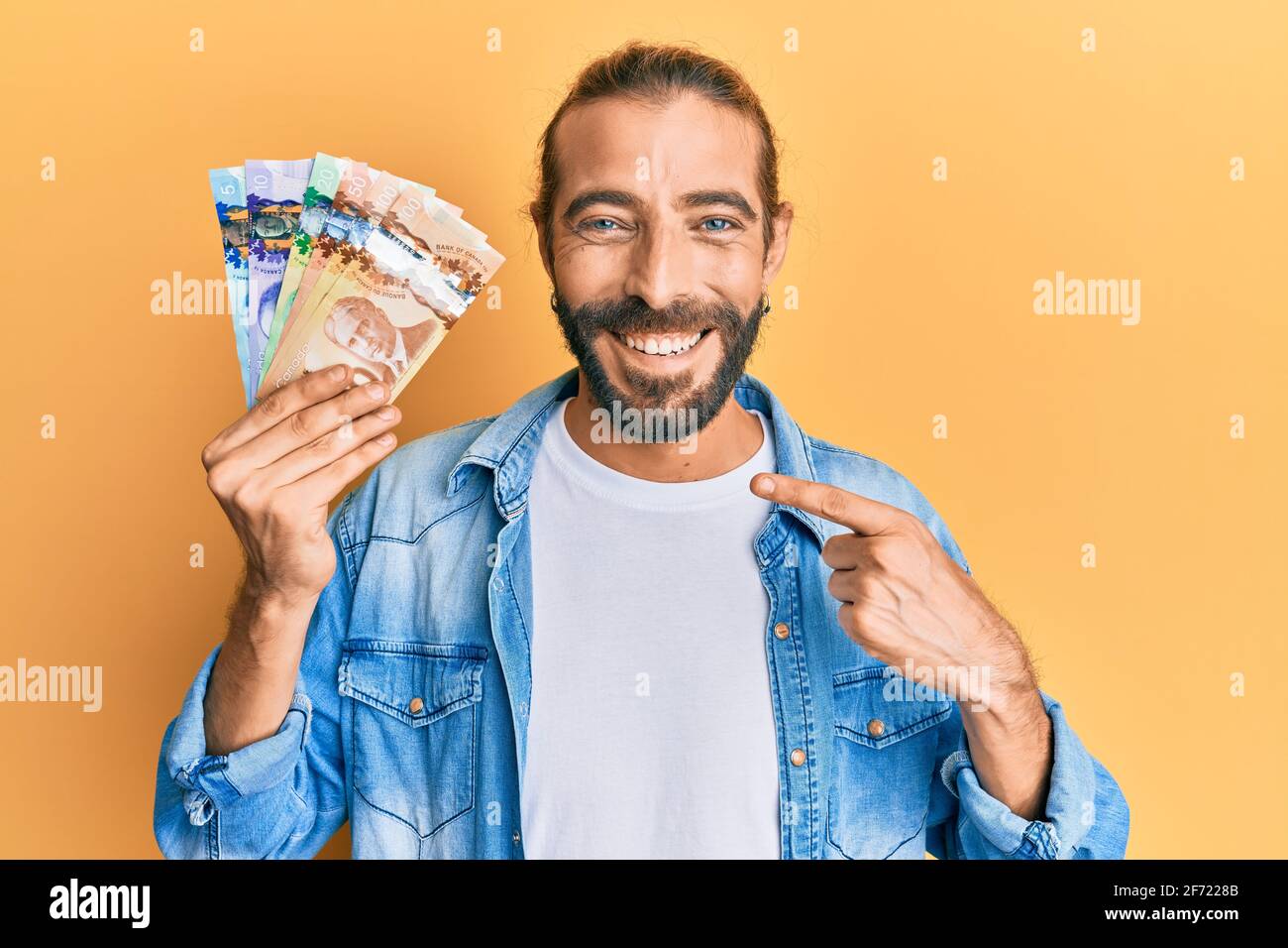 Attractive man with long hair and beard holding canadian dollars ...