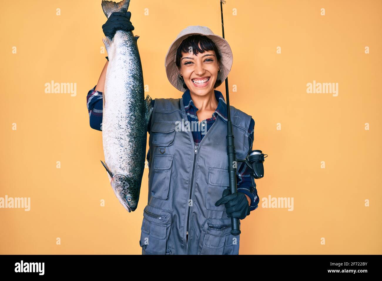 Beautiful brunettte fisher woman holding fishing rod and raw salmon ...
