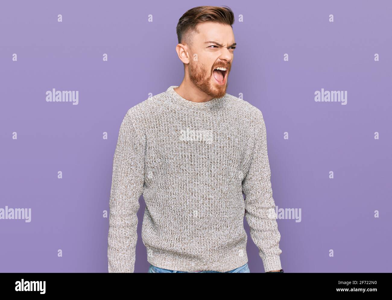 Young redhead man wearing casual winter sweater angry and mad screaming ...