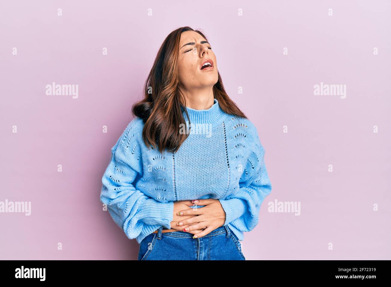 Young brunette woman wearing casual winter sweater over pink background ...