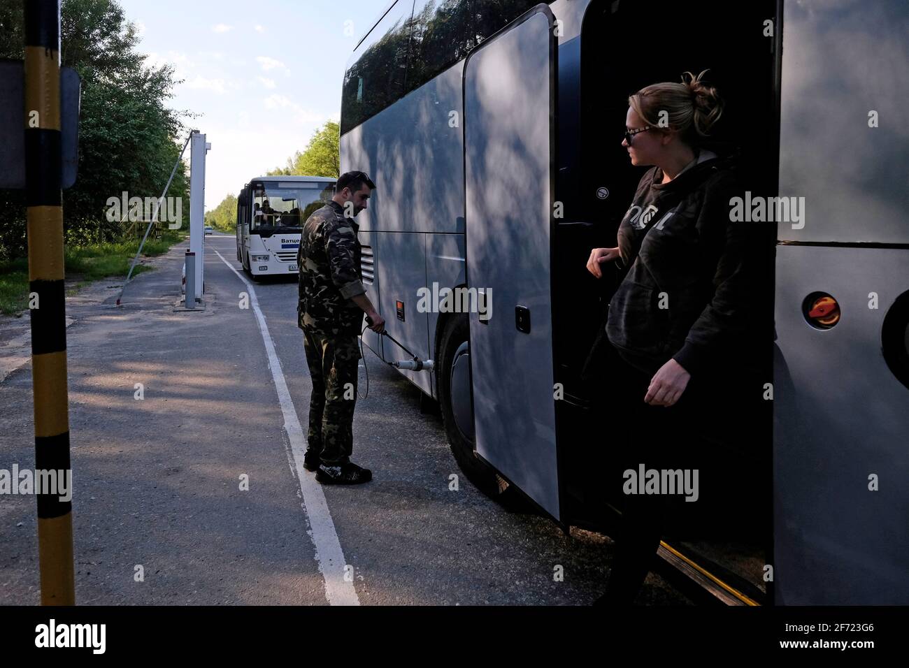 A security guard using portable radiation detector checks a bus passing ...