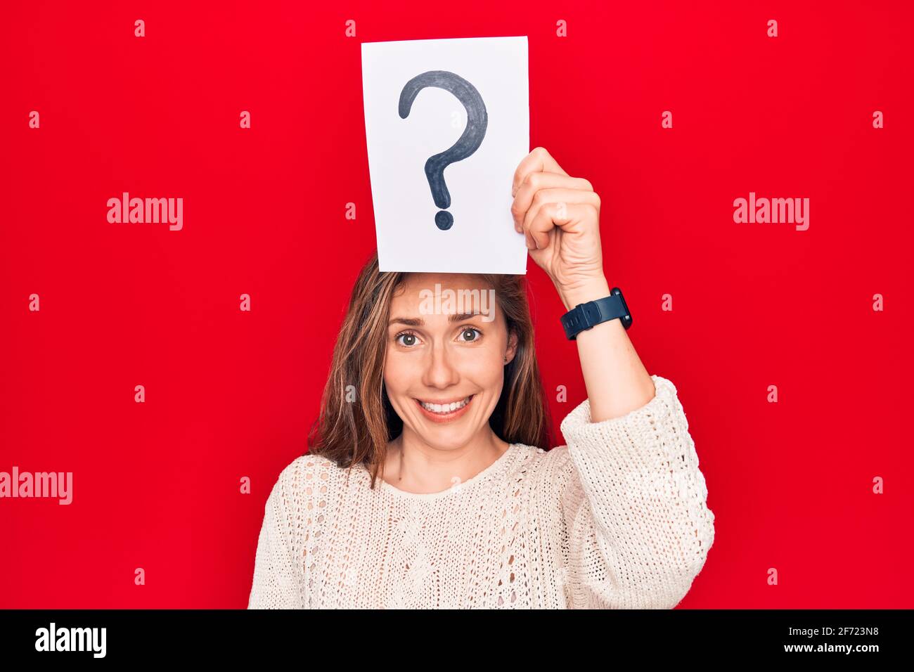 Young beautiful blonde woman holding question mark over head looking ...