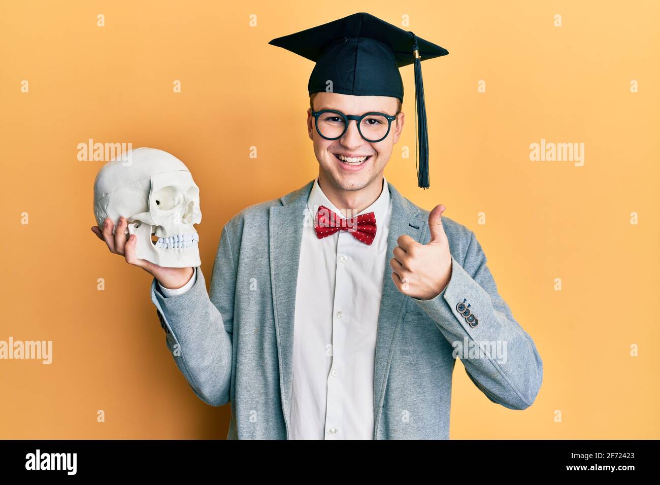 Young caucasian nerd man wearing glasses and graduation cap holding ...