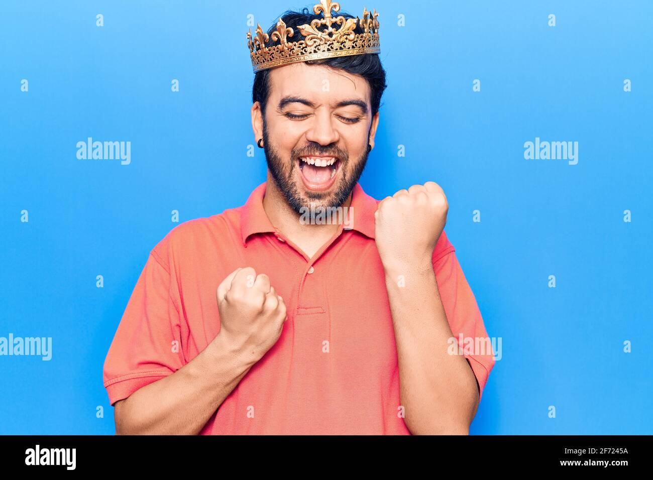 Young hispanic man wearing king crown celebrating surprised and amazed ...