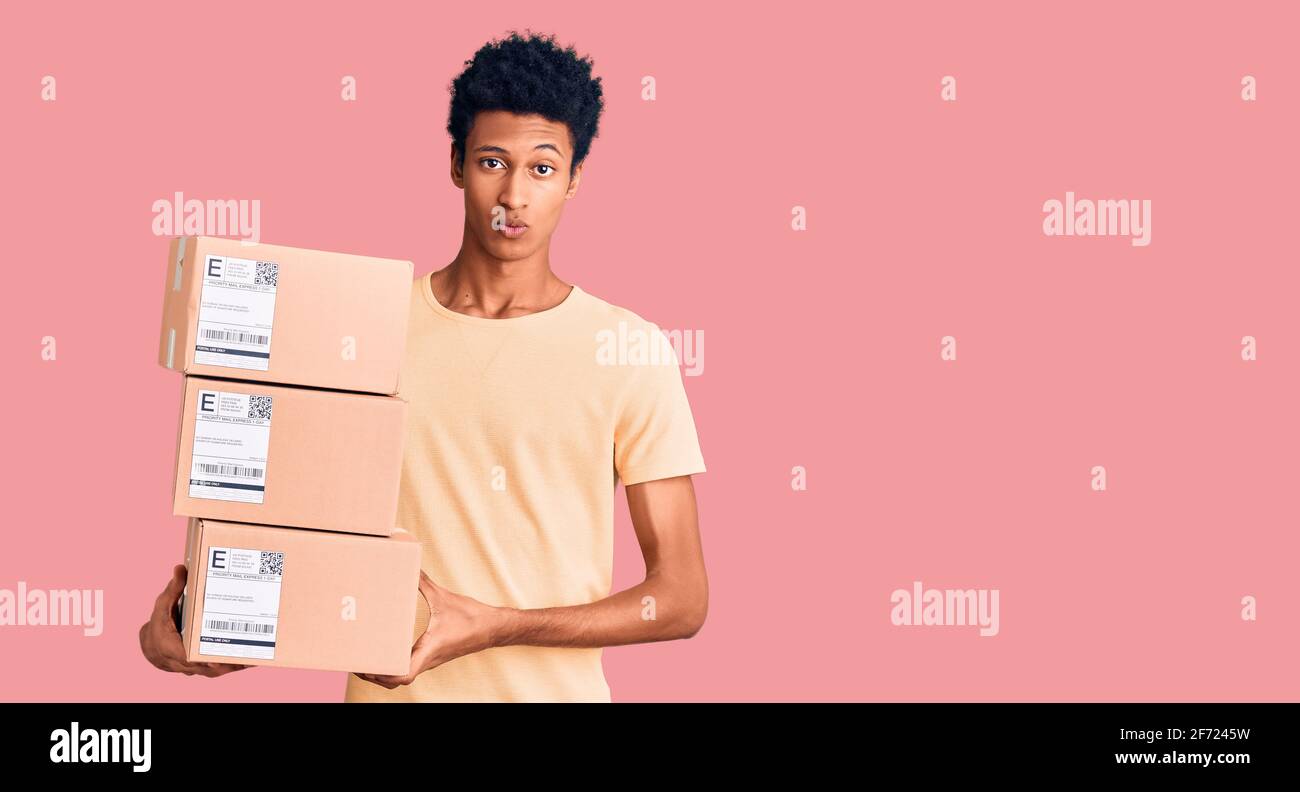 Young african american man holding delivery package thinking attitude ...