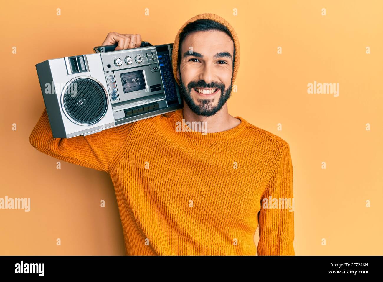 Young hispanic man holding boombox, listening to music looking positive ...
