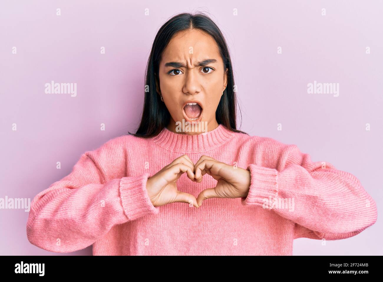 Young asian woman doing heart symbol with hands in shock face, looking ...