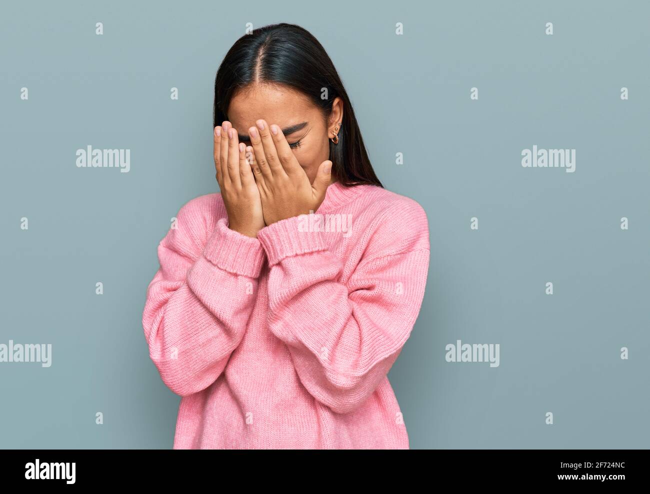 Young asian woman wearing casual winter sweater with sad expression ...