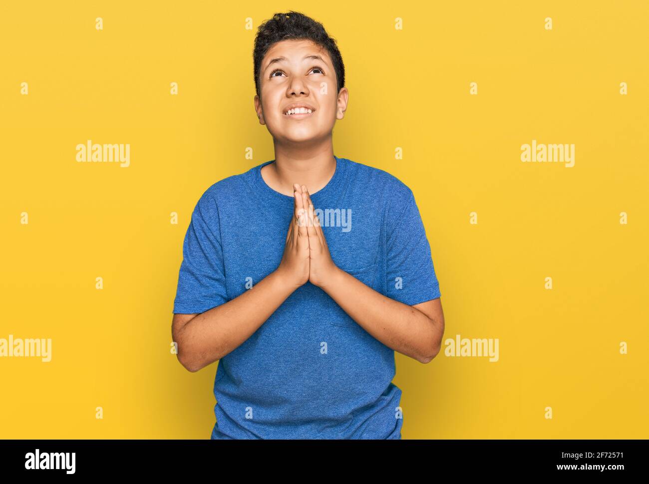 Teenager hispanic boy wearing casual clothes begging and praying with ...