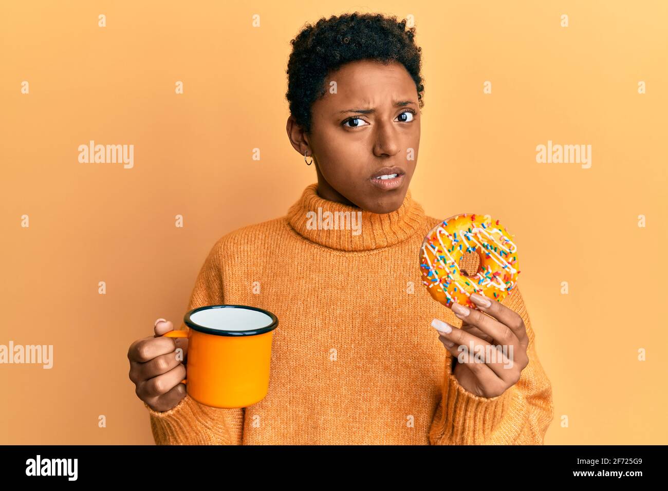 Young african american girl eating doughnut and drinking coffee ...