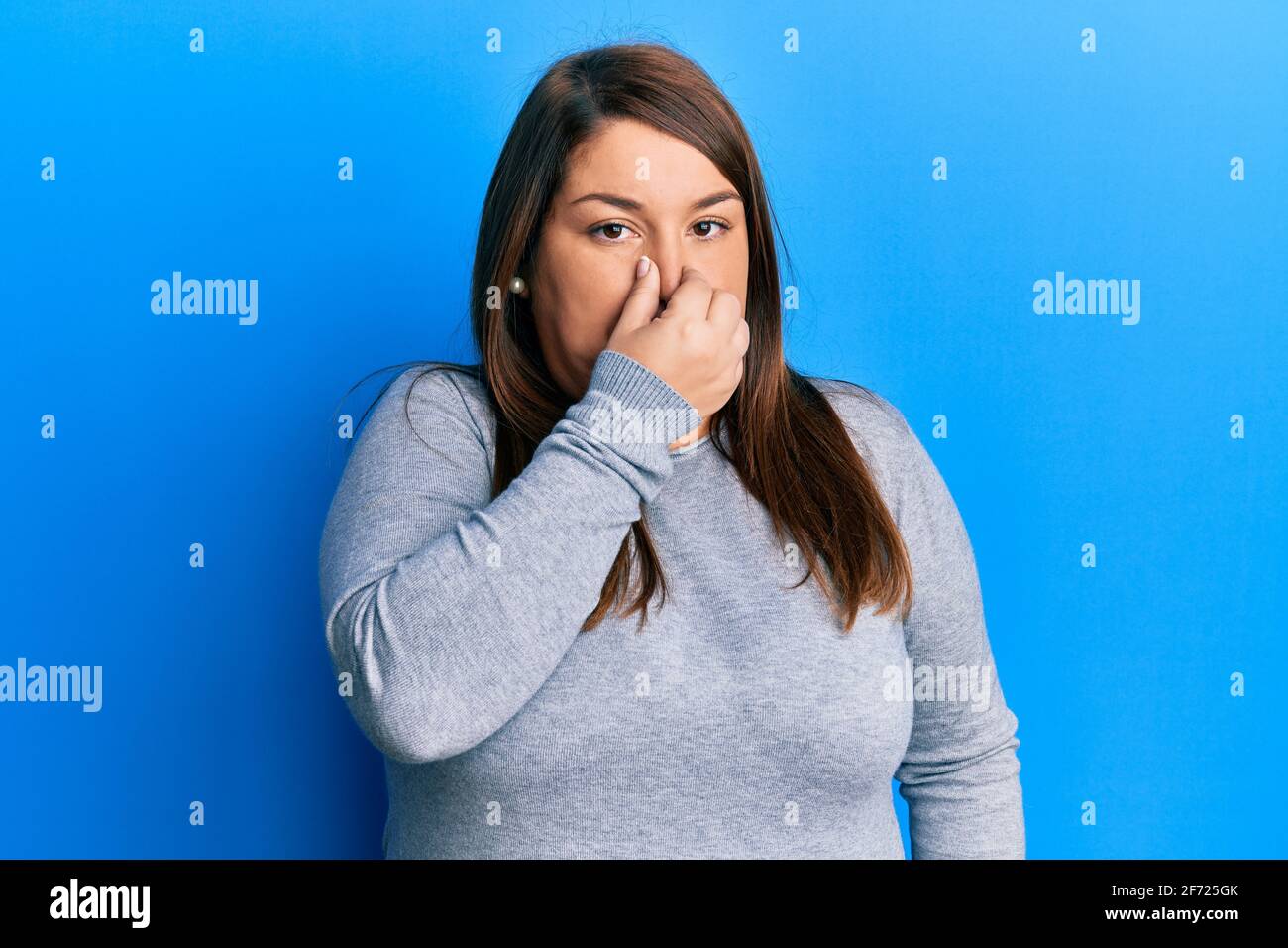 Beautiful brunette plus size woman wearing casual clothes smelling ...