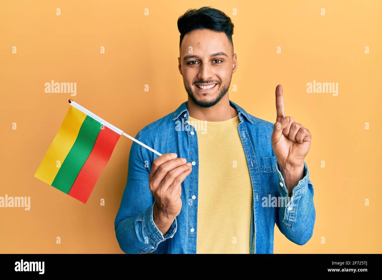 Young arab man holding lithuania flag smiling with an idea or question ...