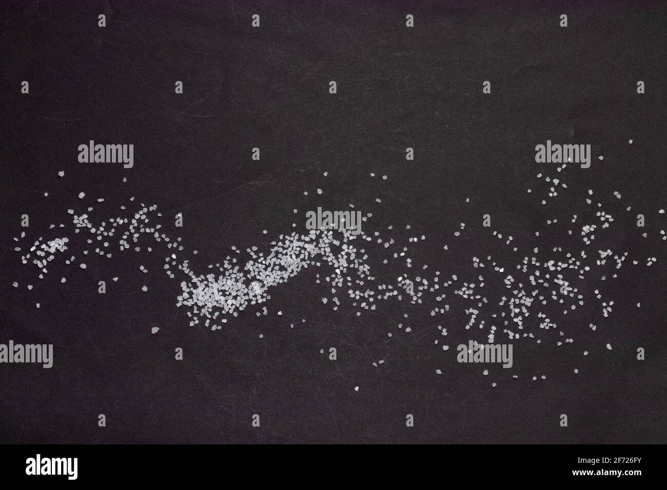 Sifting sea salt over darck background Stock Photo - Alamy